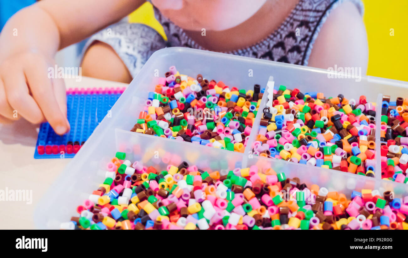 Little girl making bracelet from colorful kids beads Stock Photo - Alamy