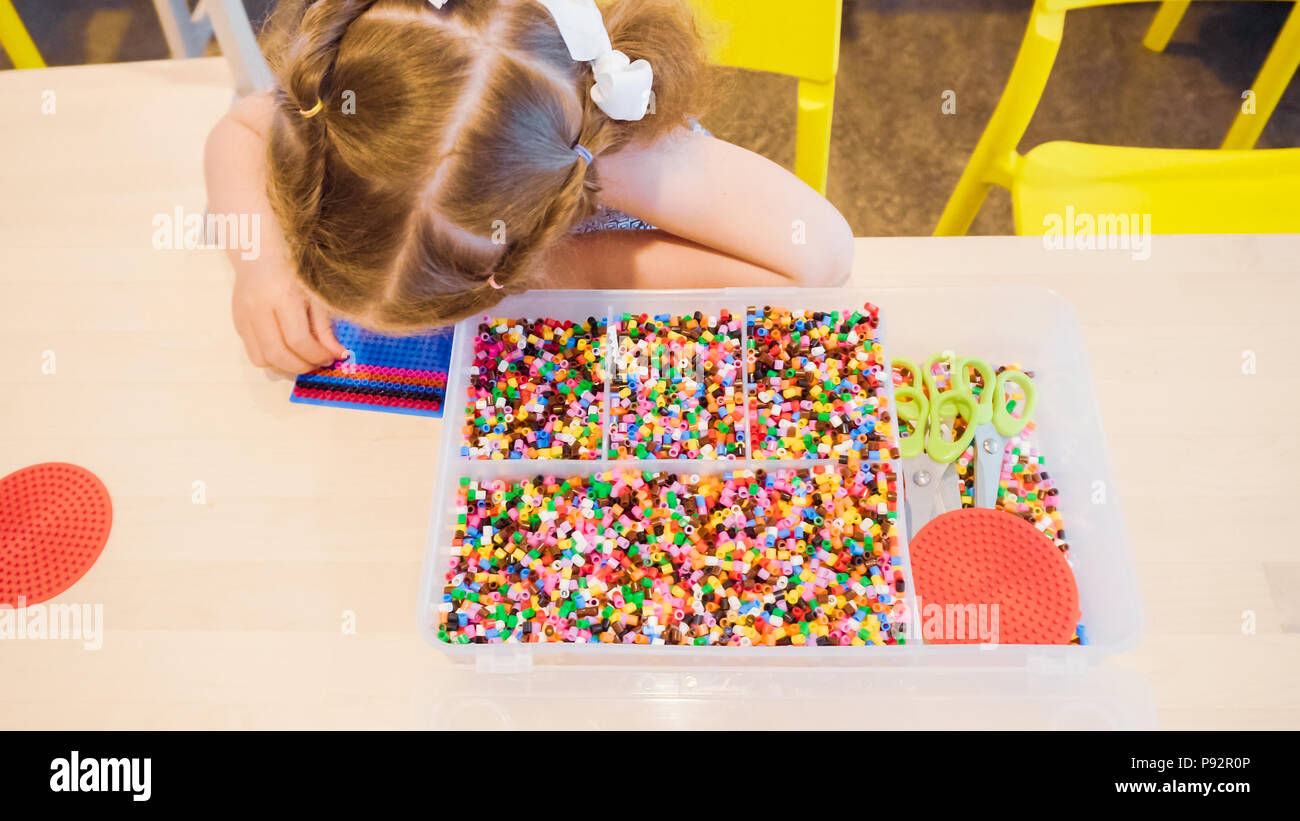 Little girl making bracelet from colorful kids beads Stock Photo - Alamy