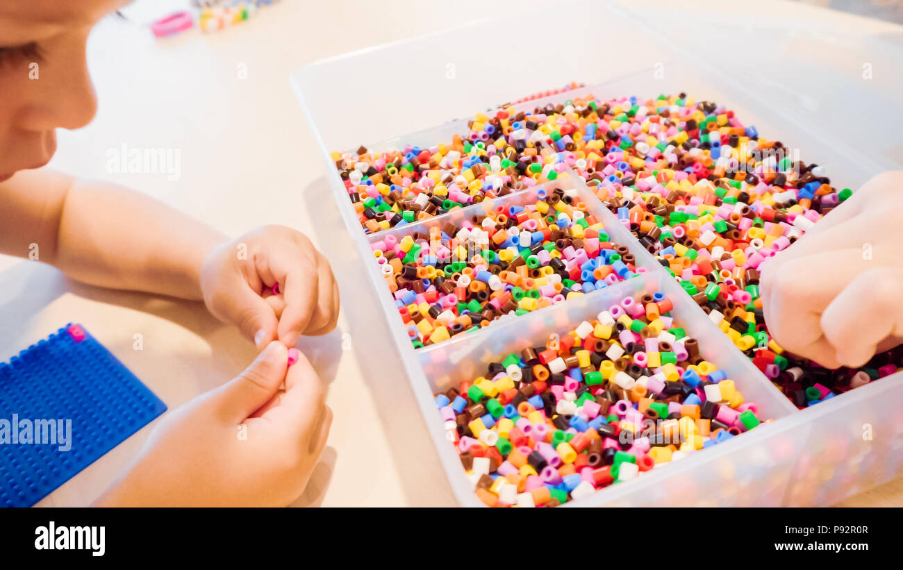 Little girl making bracelet from colorful kids beads Stock Photo - Alamy