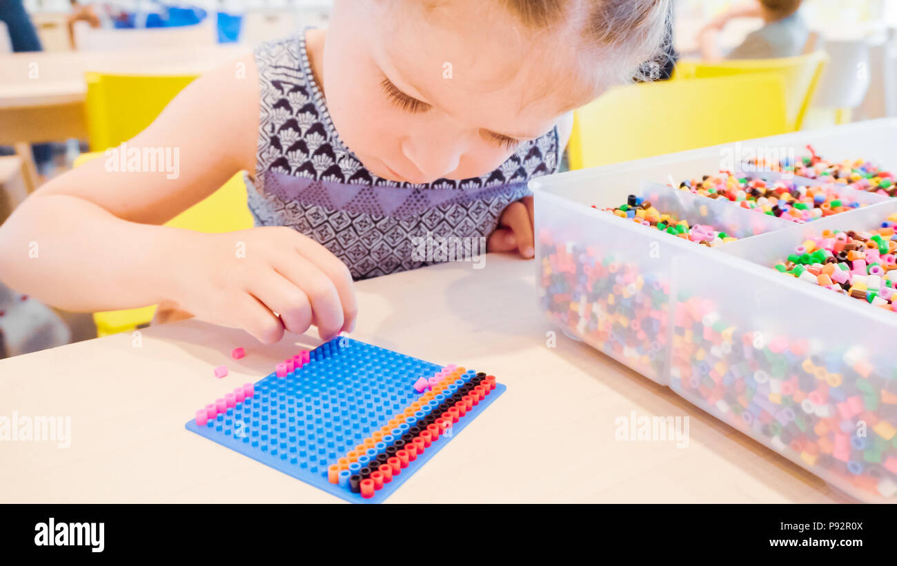 Little girl making bracelet from colorful kids beads Stock Photo - Alamy