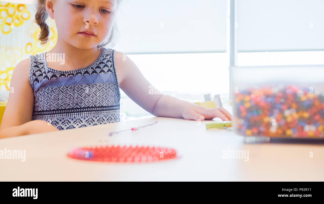 Little girl making bracelet from colorful kids beads Stock Photo - Alamy