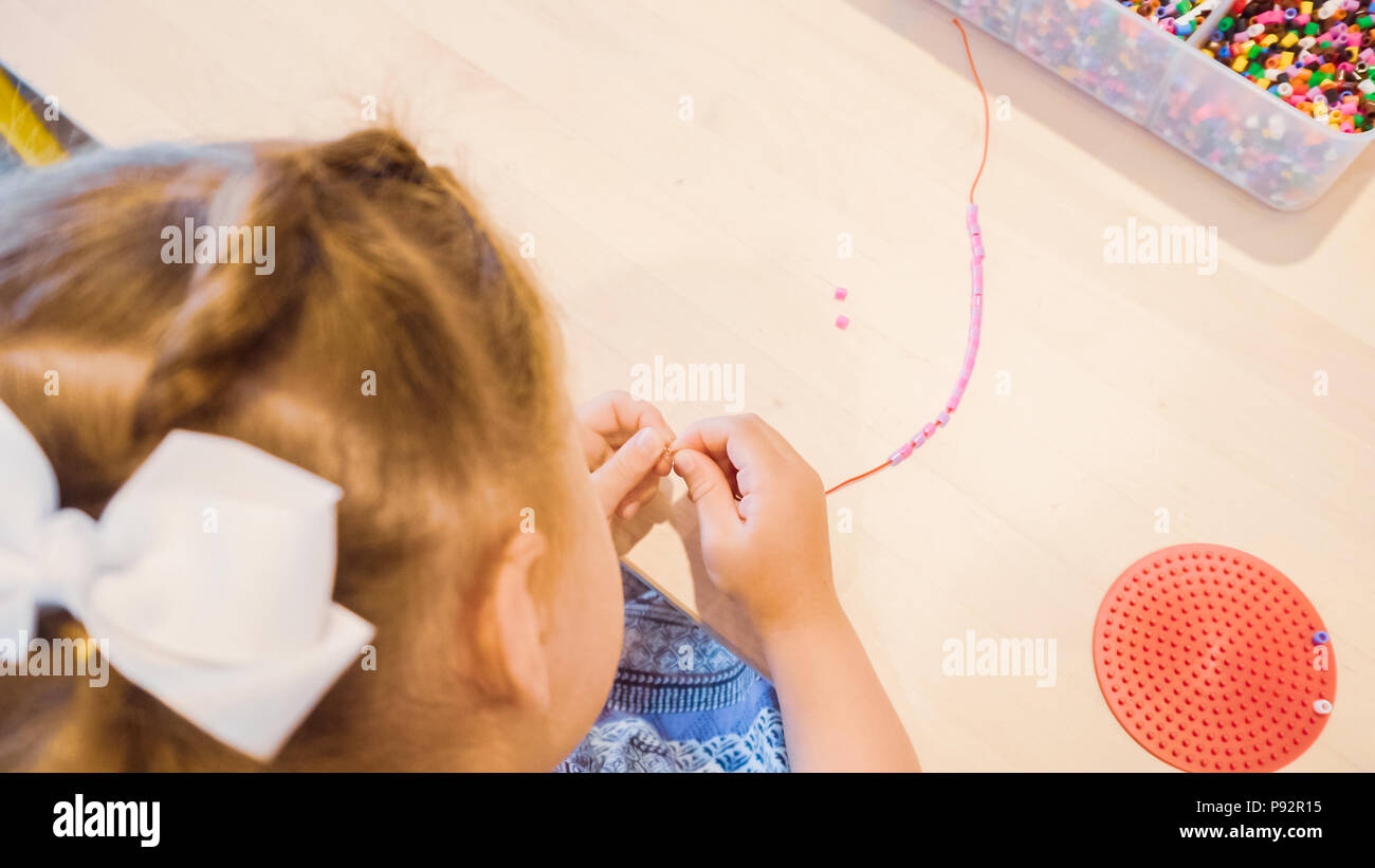 Little girl making bracelet from colorful kids beads Stock Photo - Alamy