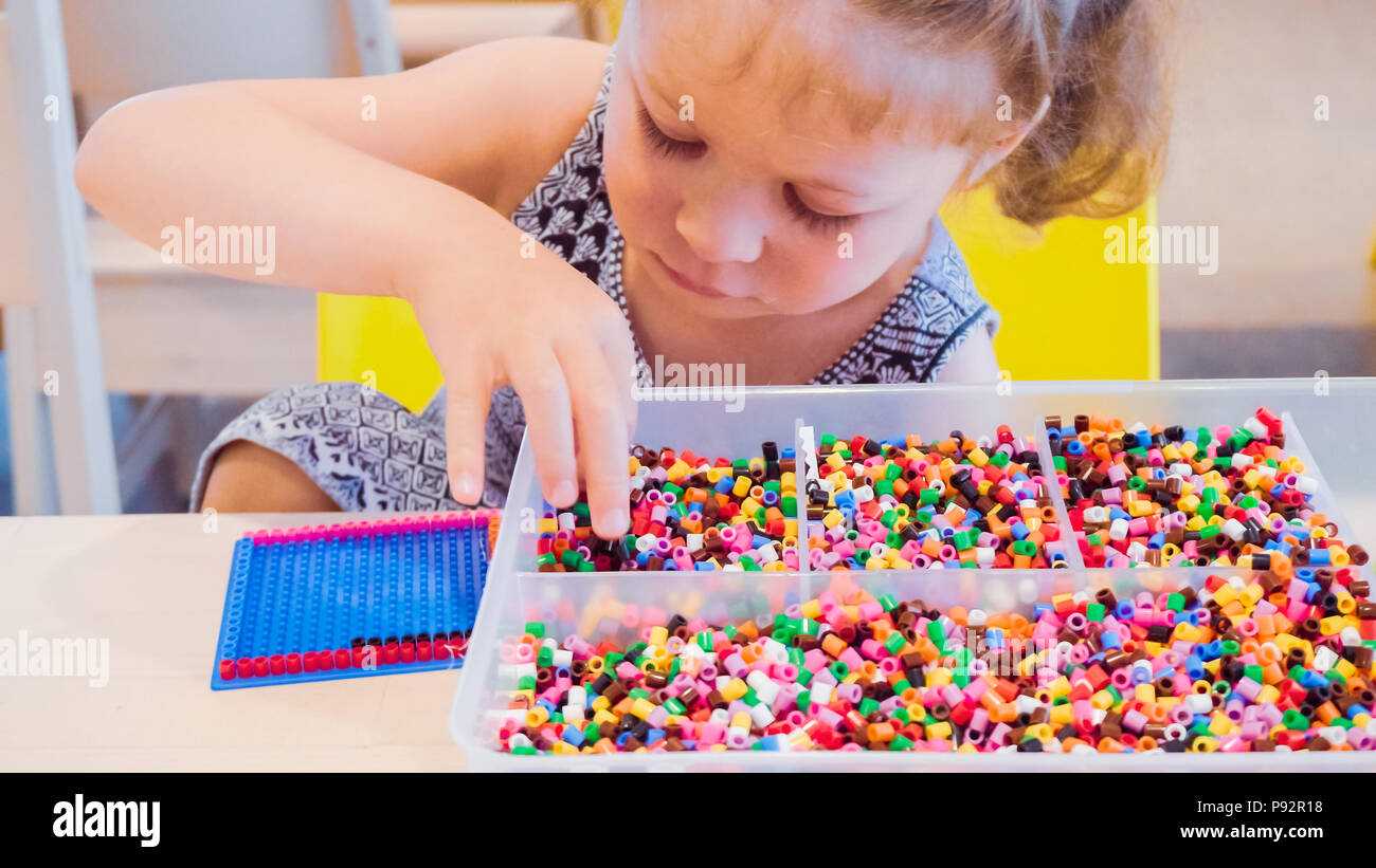 Little girl making bracelet from colorful kids beads Stock Photo - Alamy