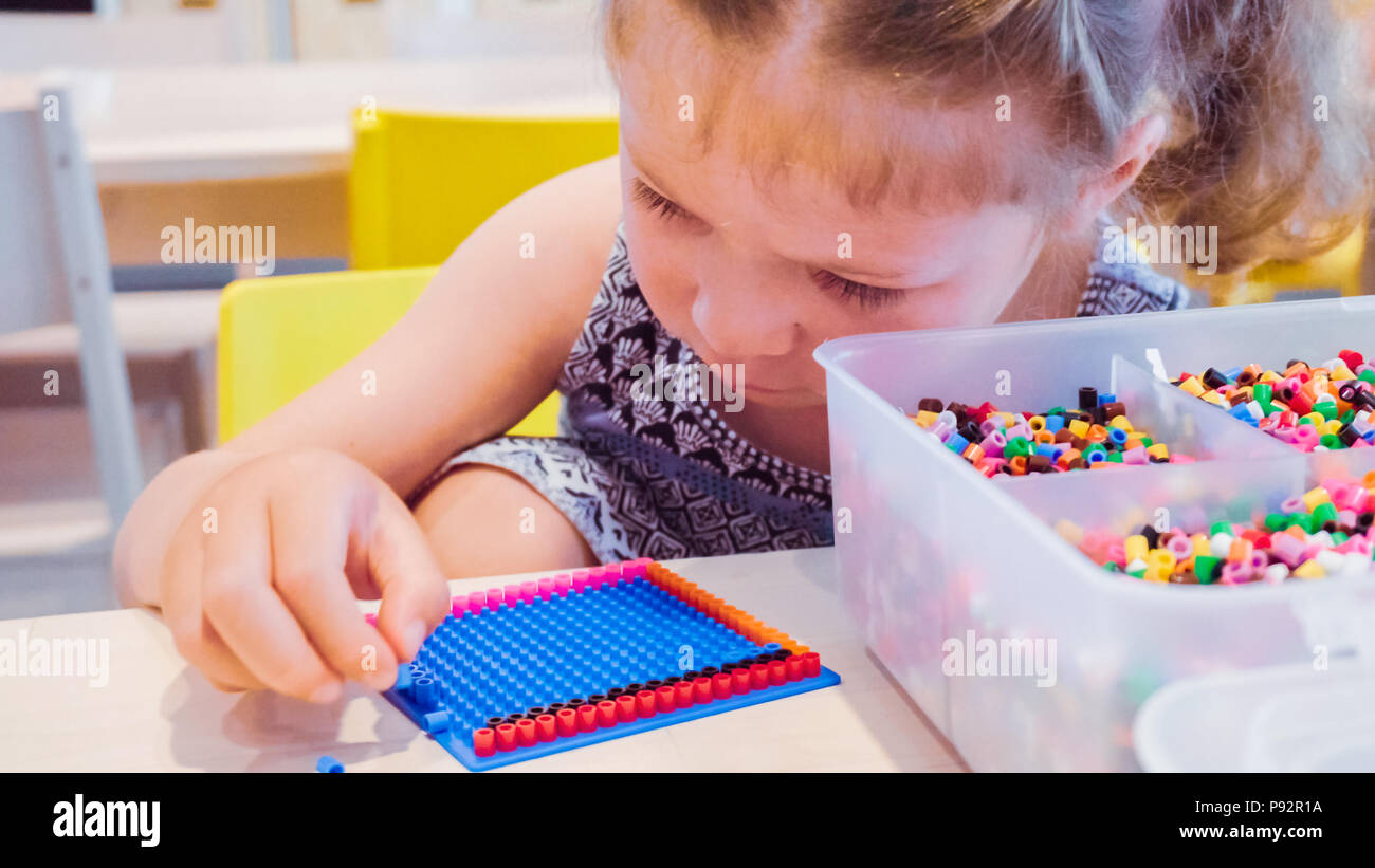 Little girl making bracelet from colorful kids beads Stock Photo - Alamy