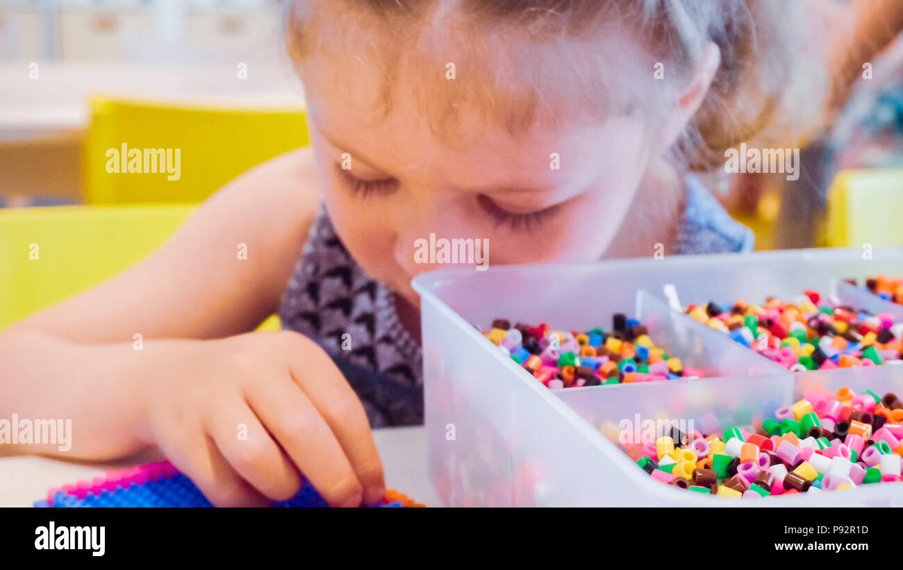 Little girl making bracelet from colorful kids beads Stock Photo - Alamy