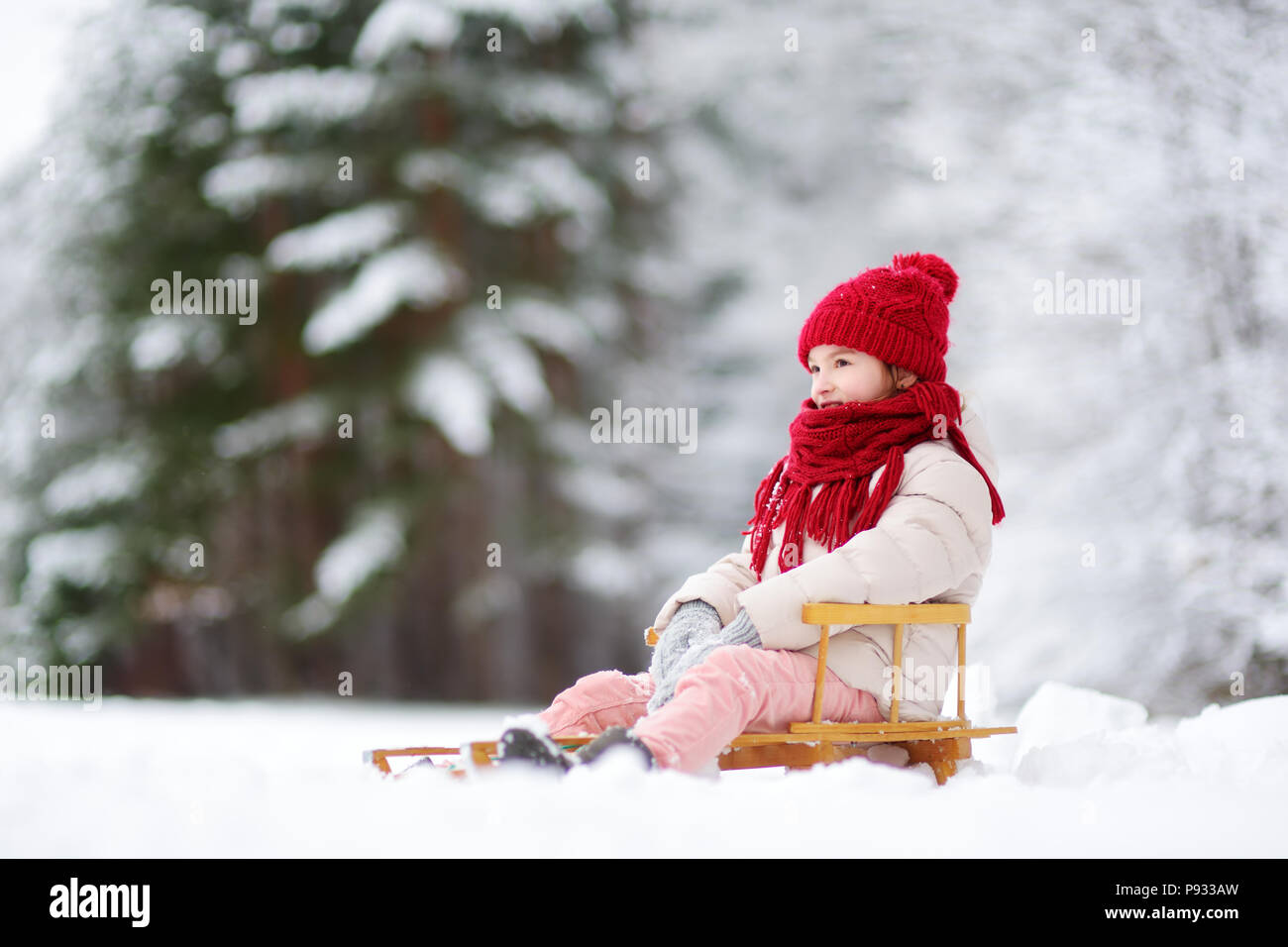 Funny little girl having fun with a sleight in beautiful winter park ...