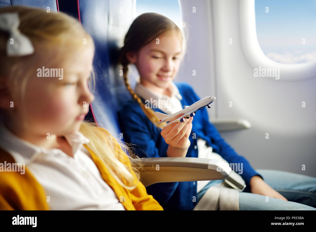 Adorable little girls traveling by an airplane. Children sitting by ...