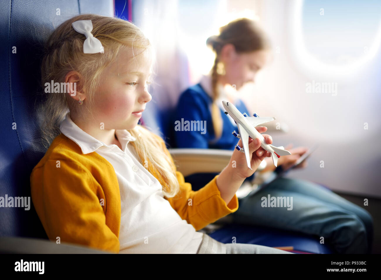 Adorable little girls traveling by an airplane. Children sitting by ...