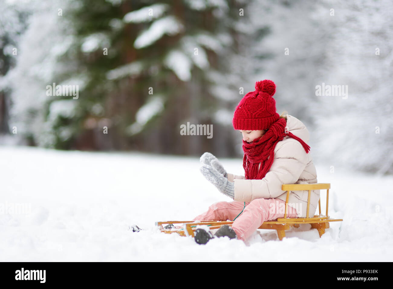Funny little girl having fun with a sleight in beautiful winter park ...