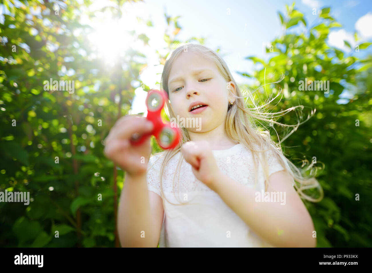 Cute school girl playing with colorful fidget spinner on the playground ...