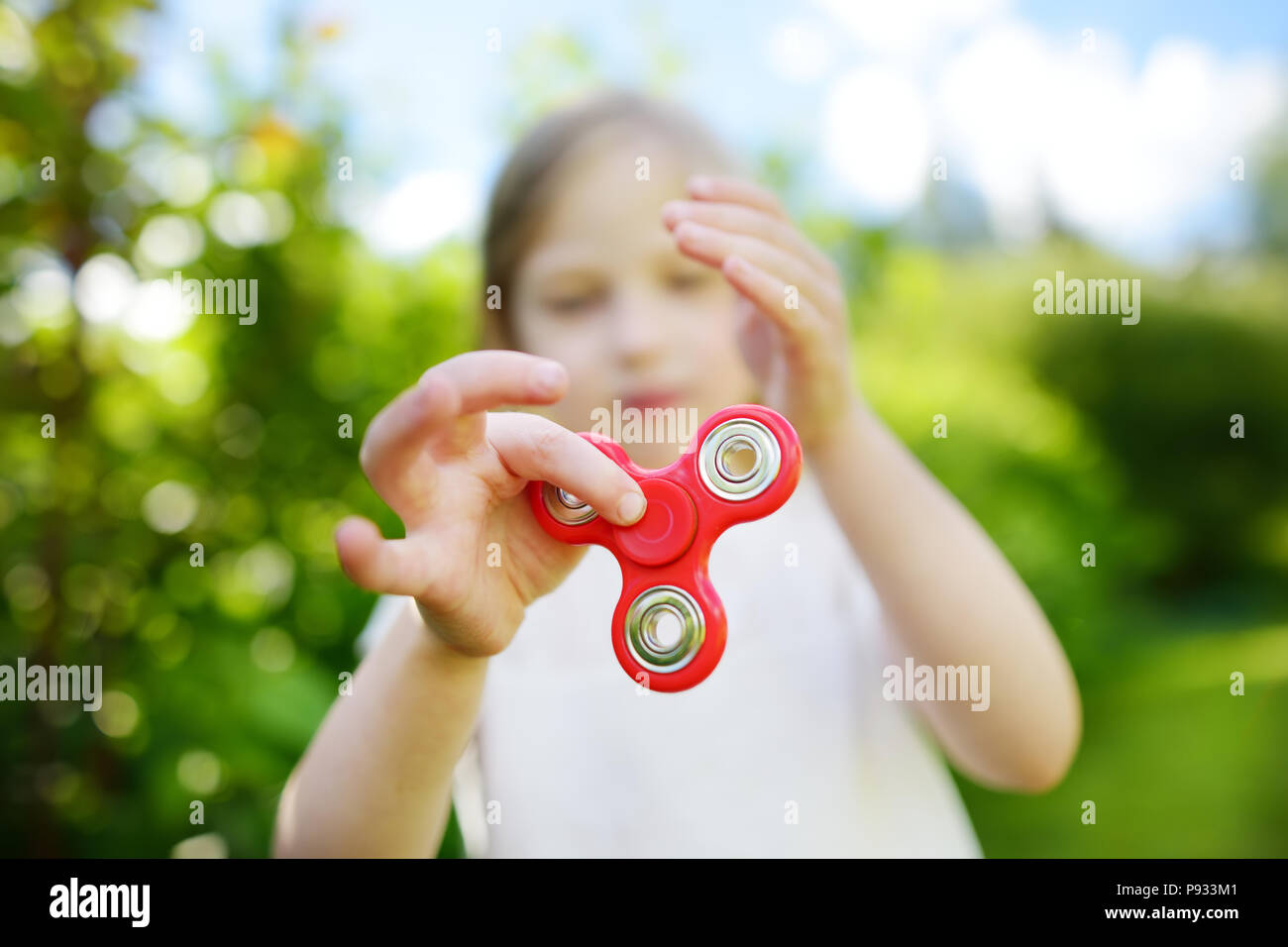 Cute school girl playing with colorful fidget spinner on the playground ...