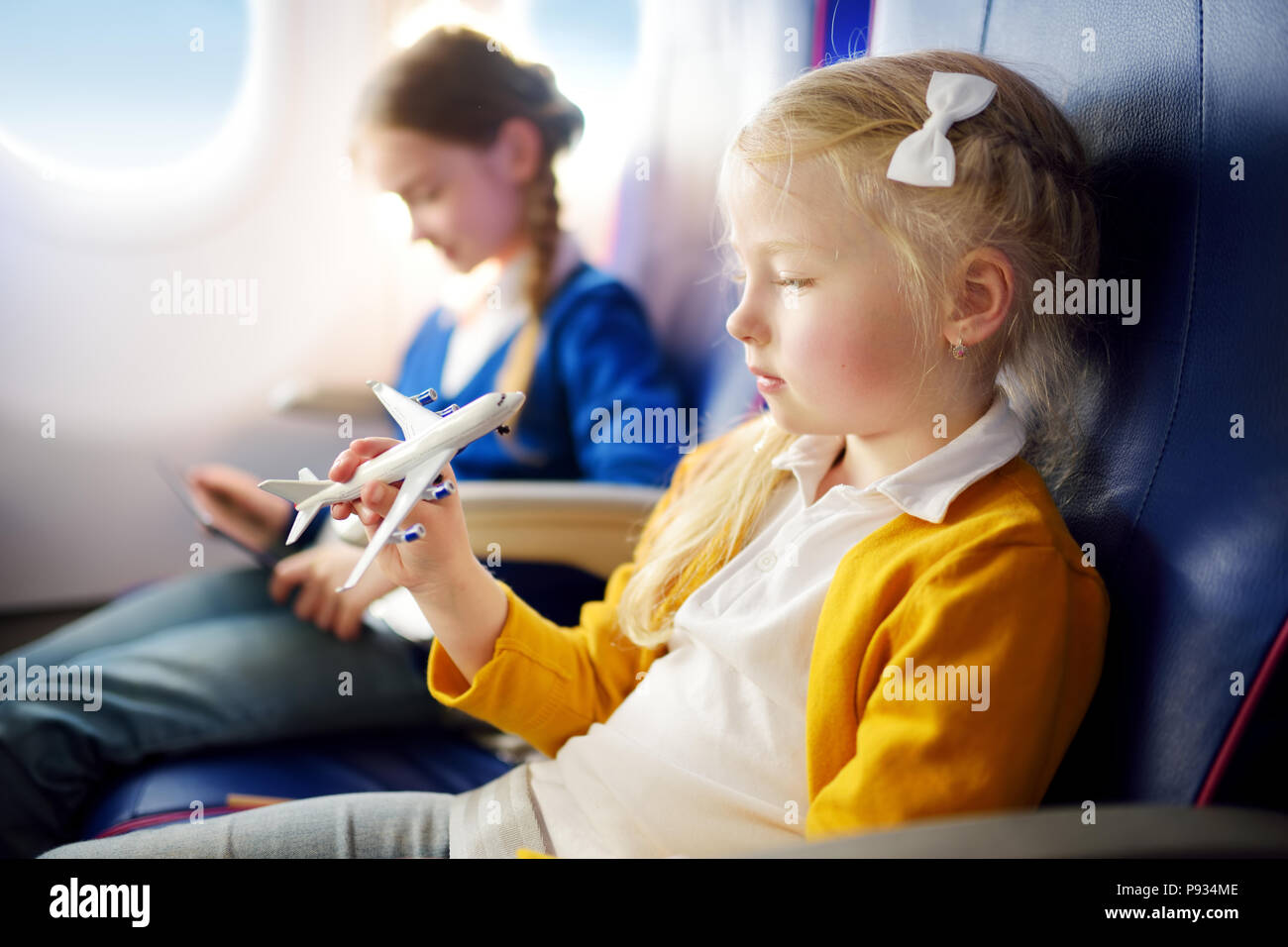 Adorable little girls traveling by an airplane. Children sitting by ...