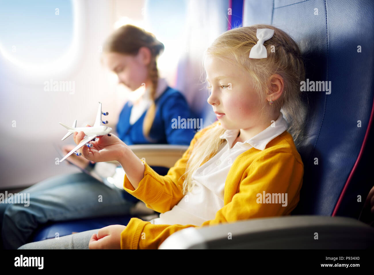 Adorable little girls traveling by an airplane. Children sitting by ...