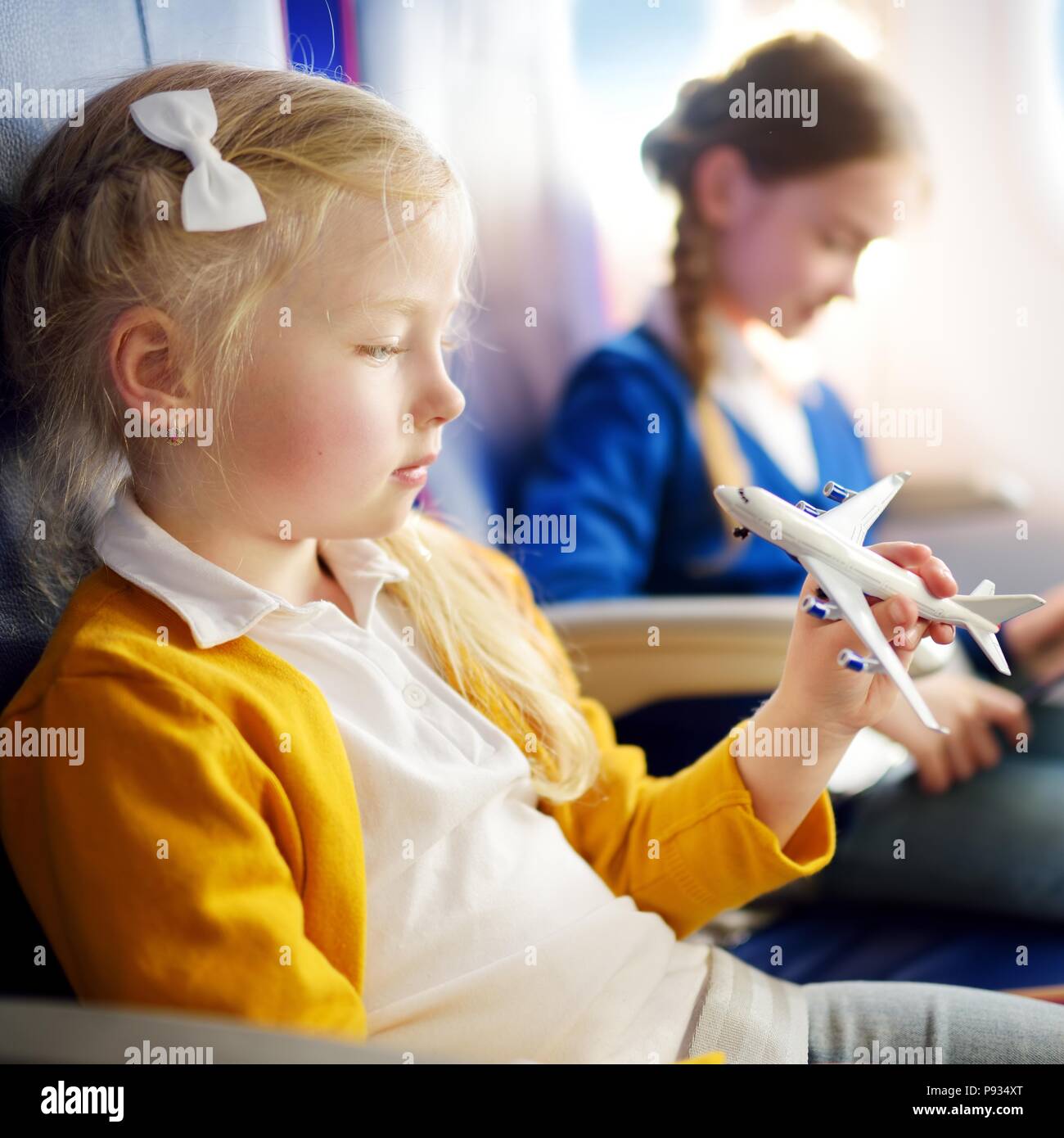 Adorable little girls traveling by an airplane. Children sitting by ...