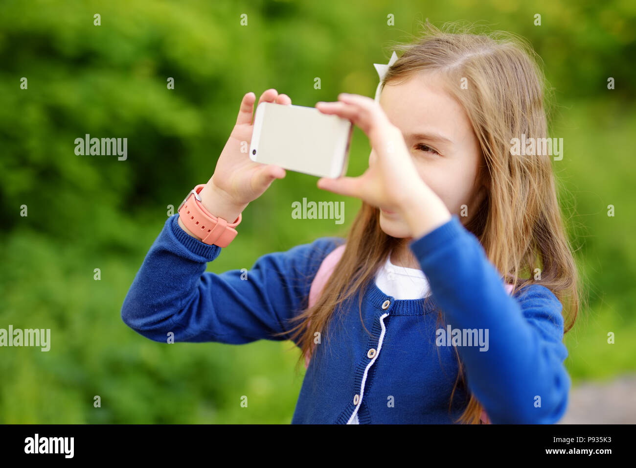 Adorable little girl taking a photo with a smartphone on beautiful ...