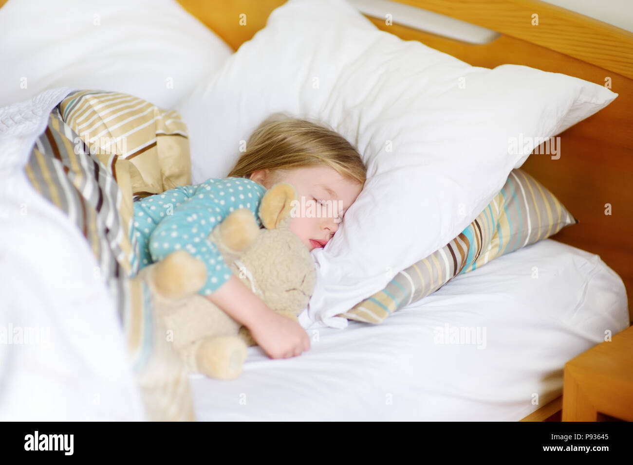 Adorable little girl sleeping in the bed with her toy. Tired child ...