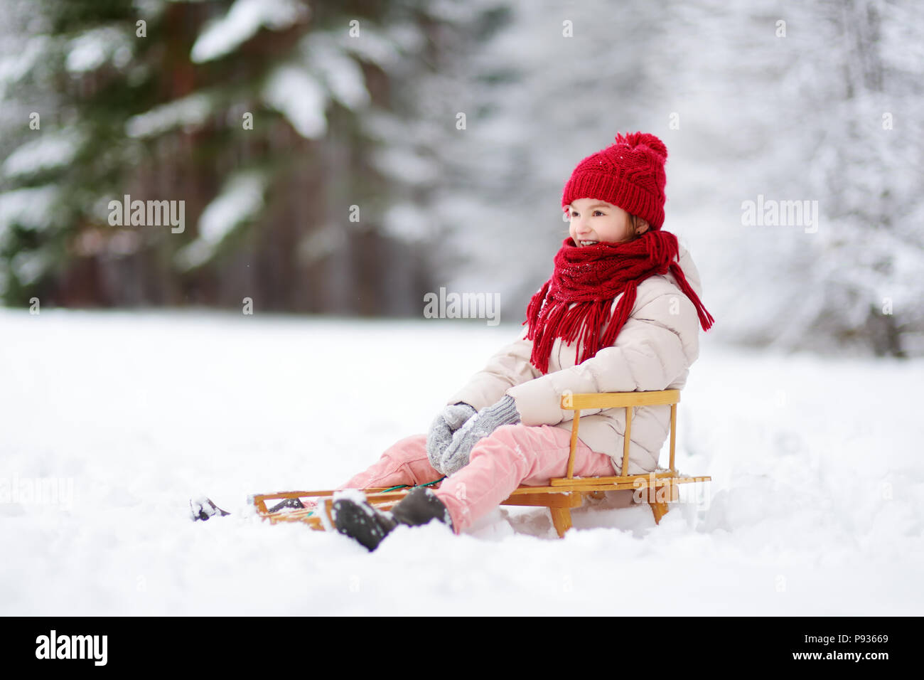 Funny little girl having fun with a sleight in beautiful winter park ...