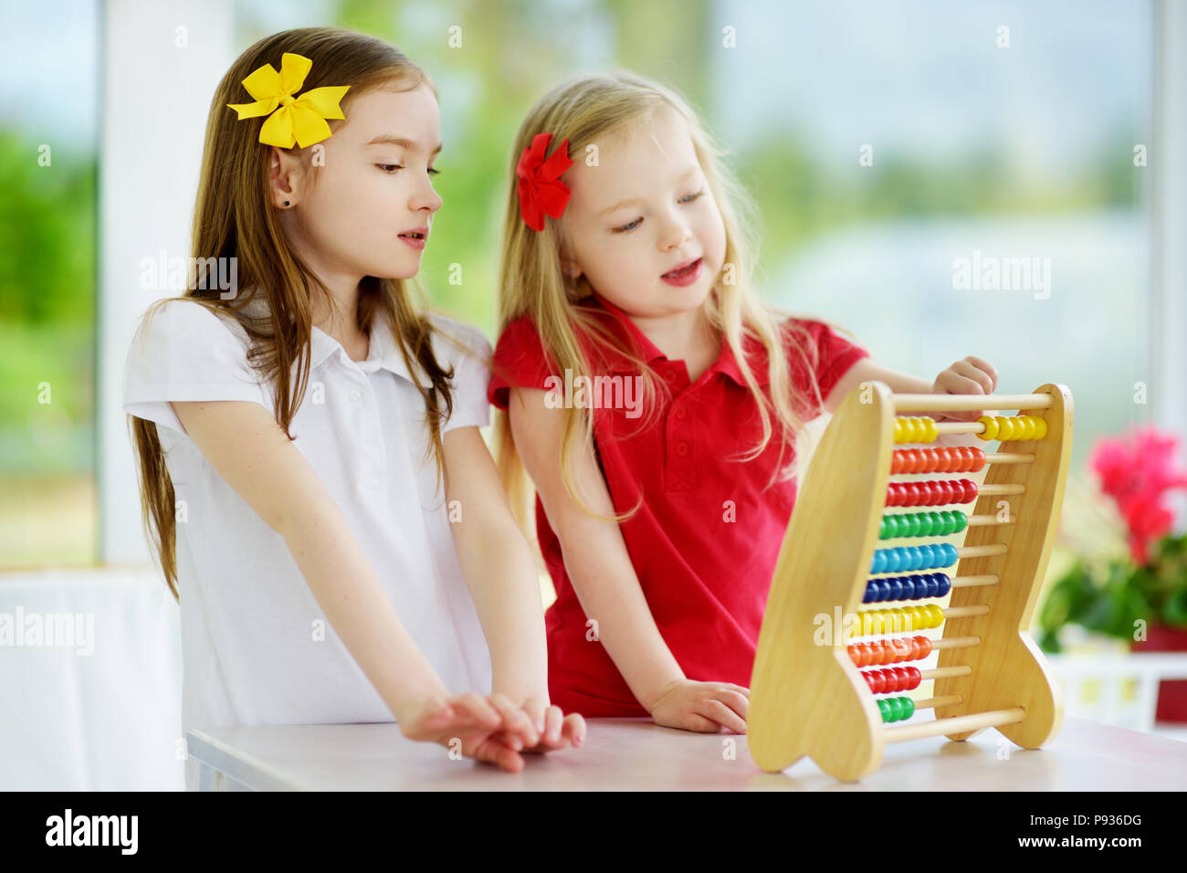Two cute little girls playing with abacus at home. Big sister teaching ...