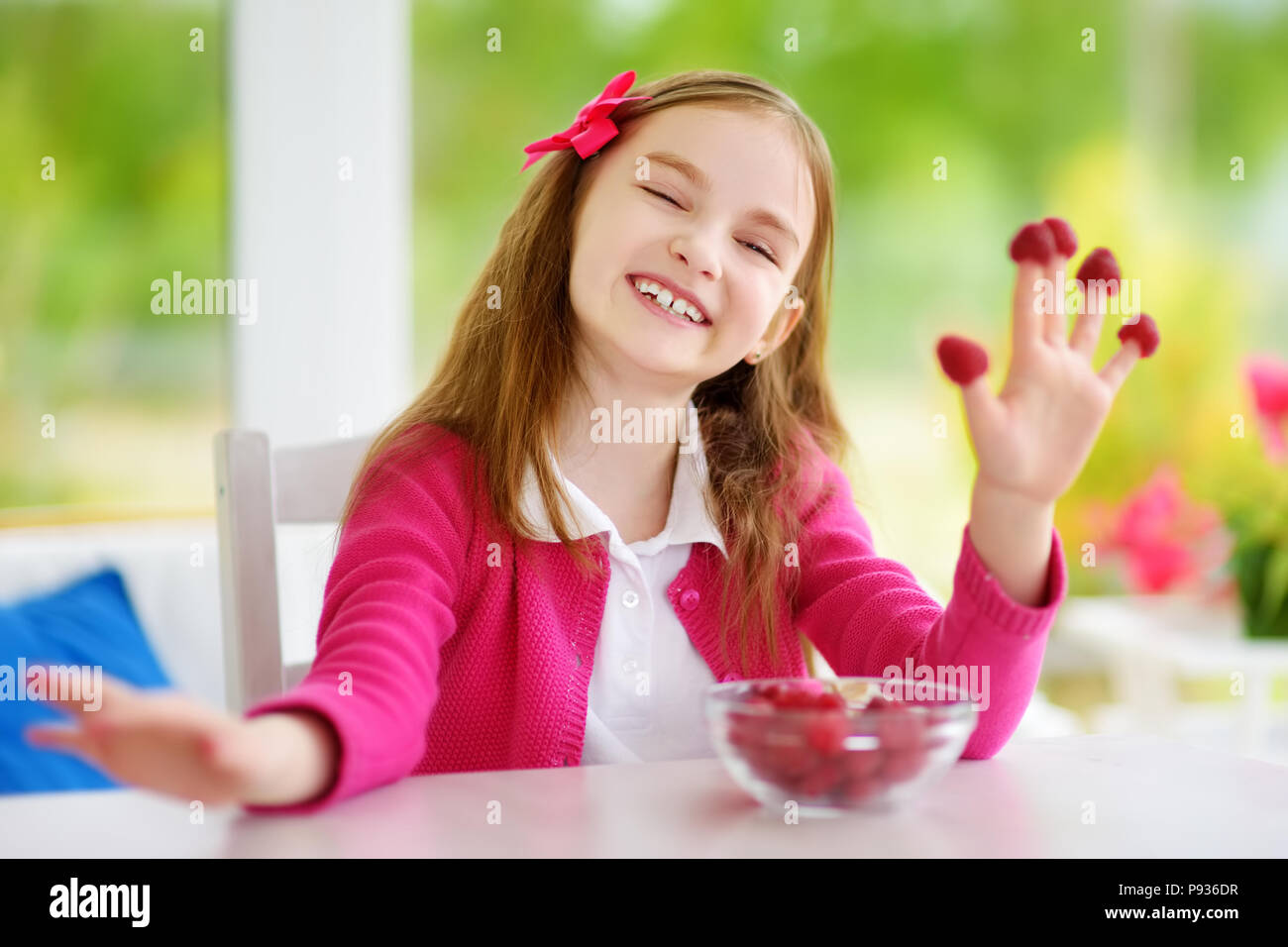 Pretty little girl eating raspberries at home. Cute child enjoying her ...