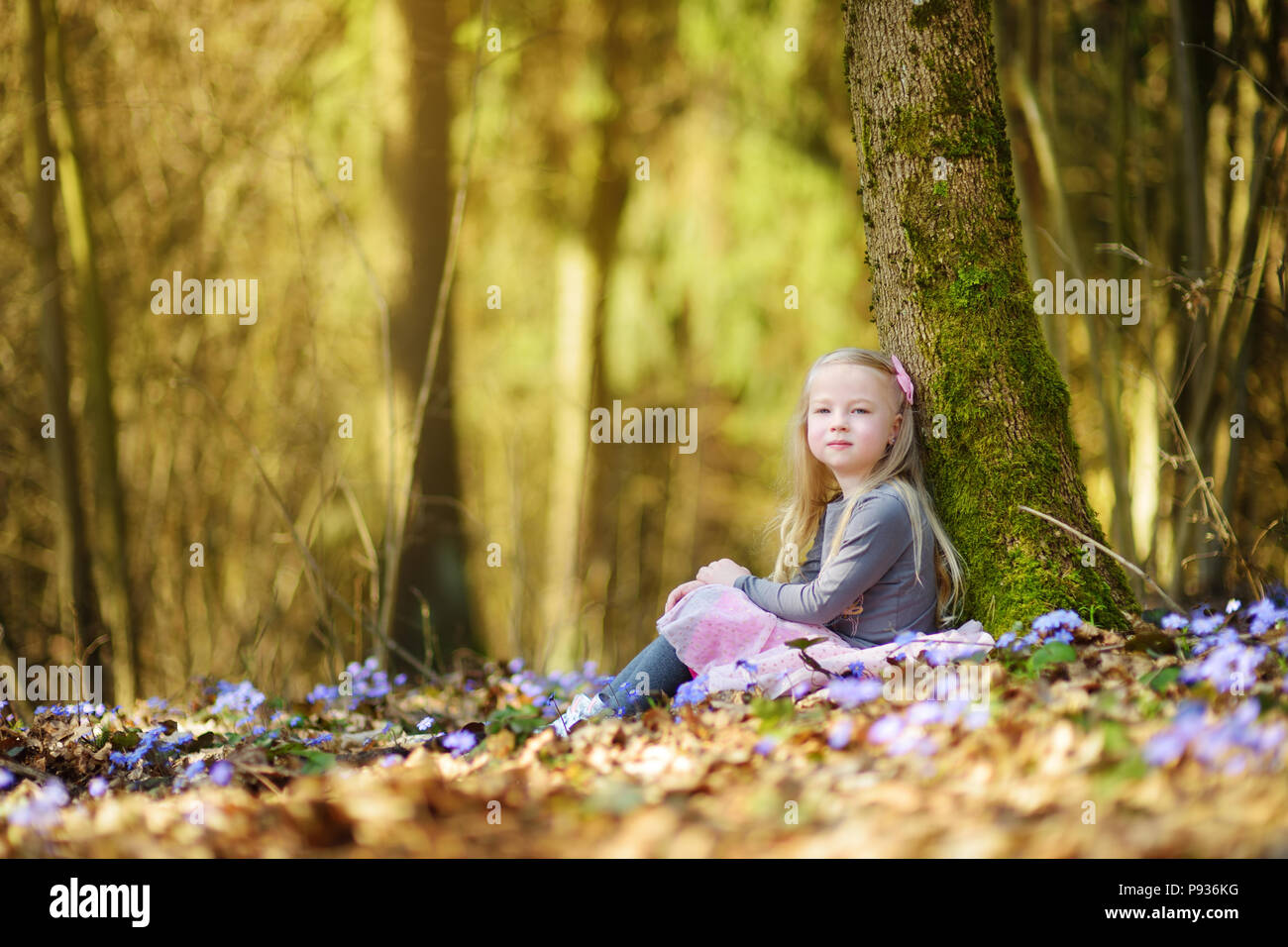 Adorable little girl picking the first flowers of spring in the woods ...
