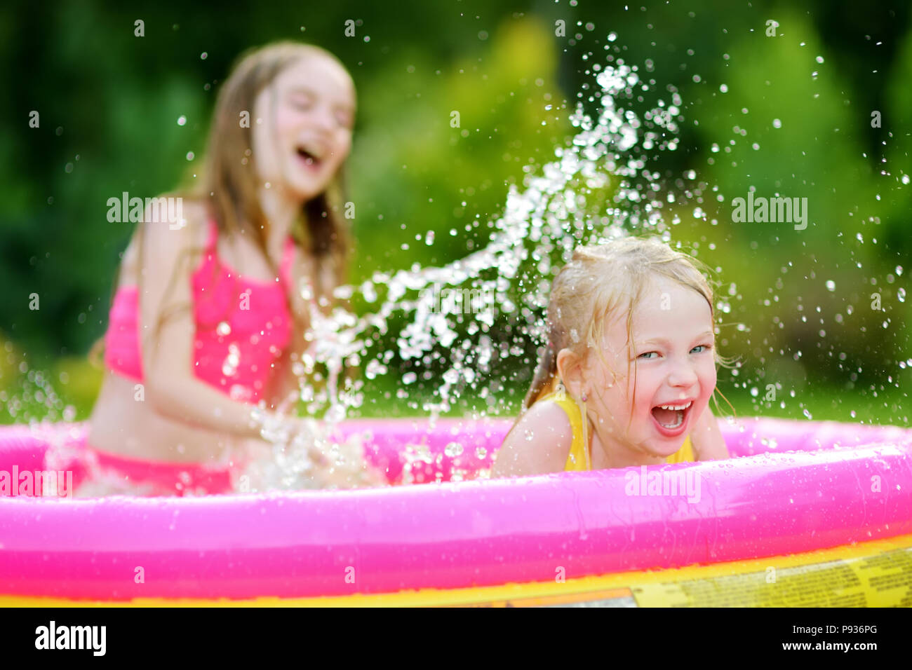 Adorable little girls playing in inflatable baby pool. Happy kids ...