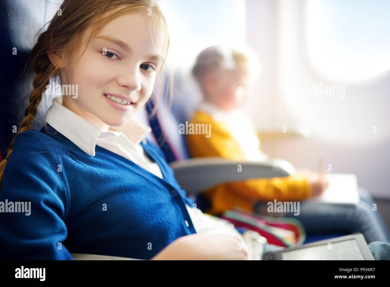 Adorable little girls traveling by an airplane. Child sitting by ...