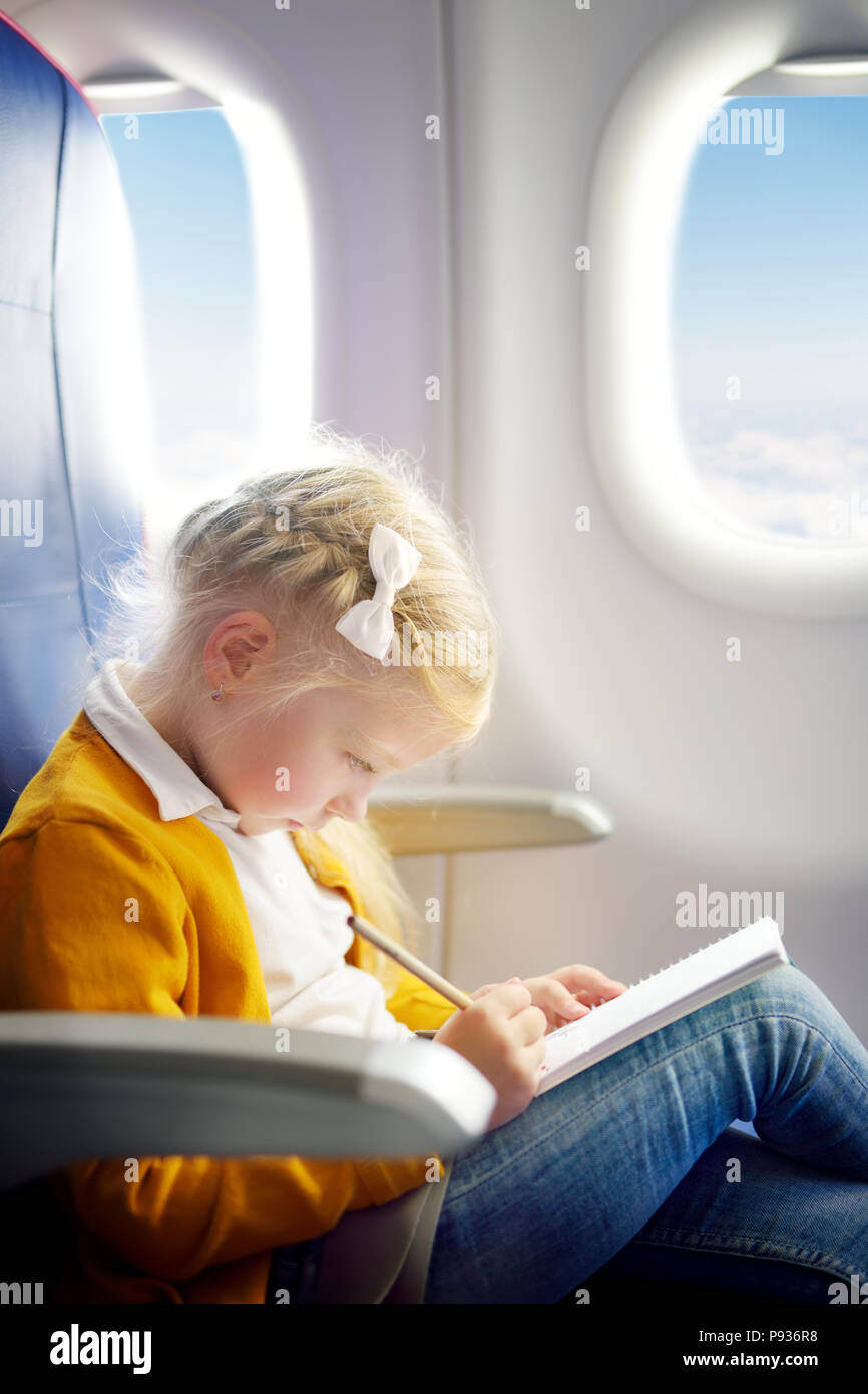 Adorable little girls traveling by an airplane. Children sitting by ...