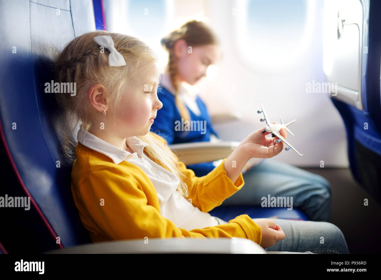 Adorable little girls traveling by an airplane. Child sitting by ...