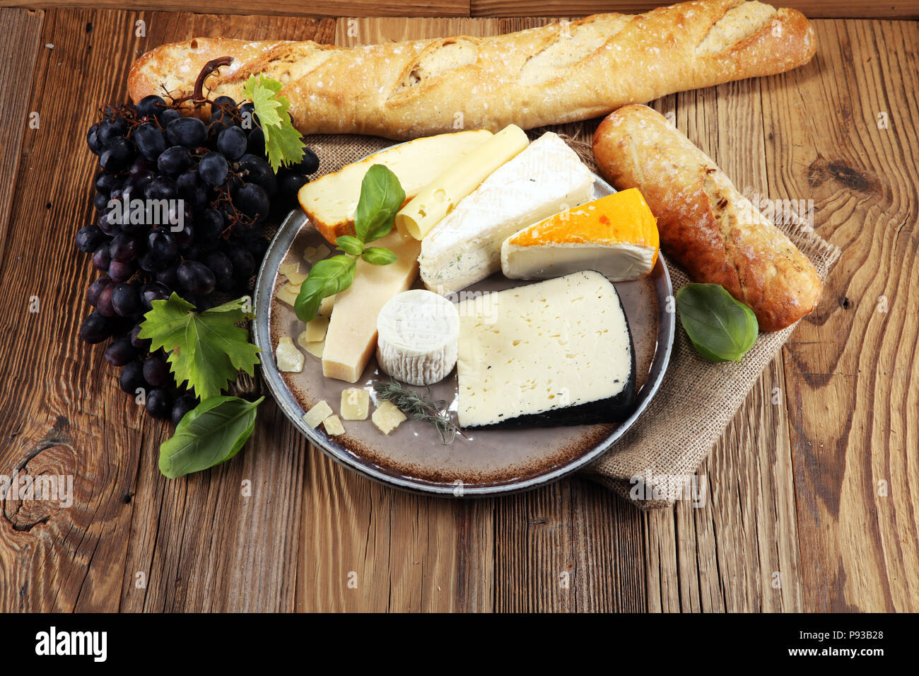 Cheese platter with different cheese on rustic plate Stock Photo - Alamy