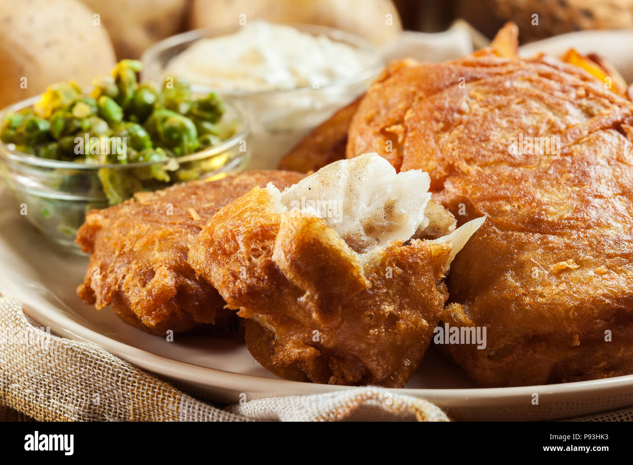 Traditional fish in beer batter and chips with green pea and tartar ...