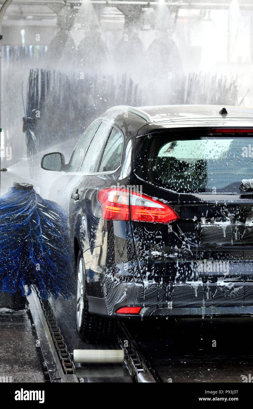 Car goes into car wash with lots of foam, rotating blue brushes and the ...