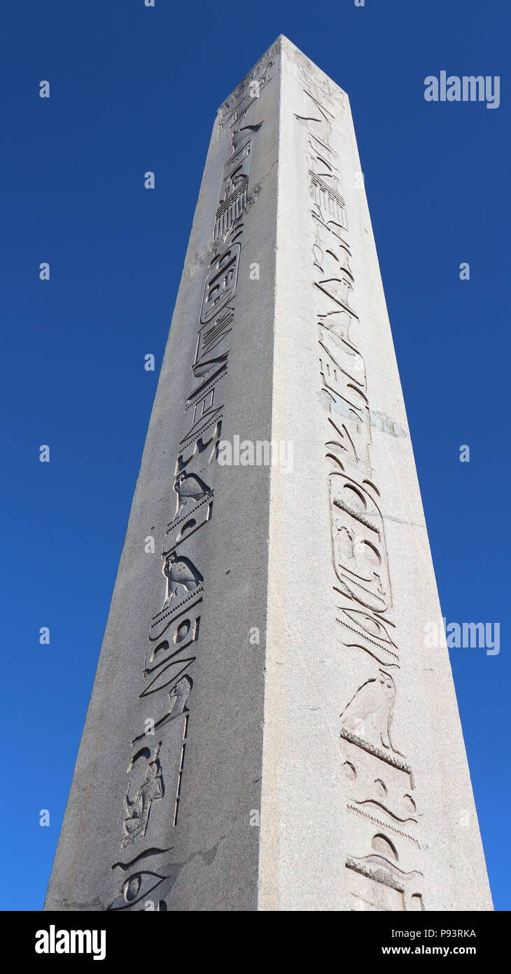 Egyptian obelisk with writing on it on a blue sky background, close up ...