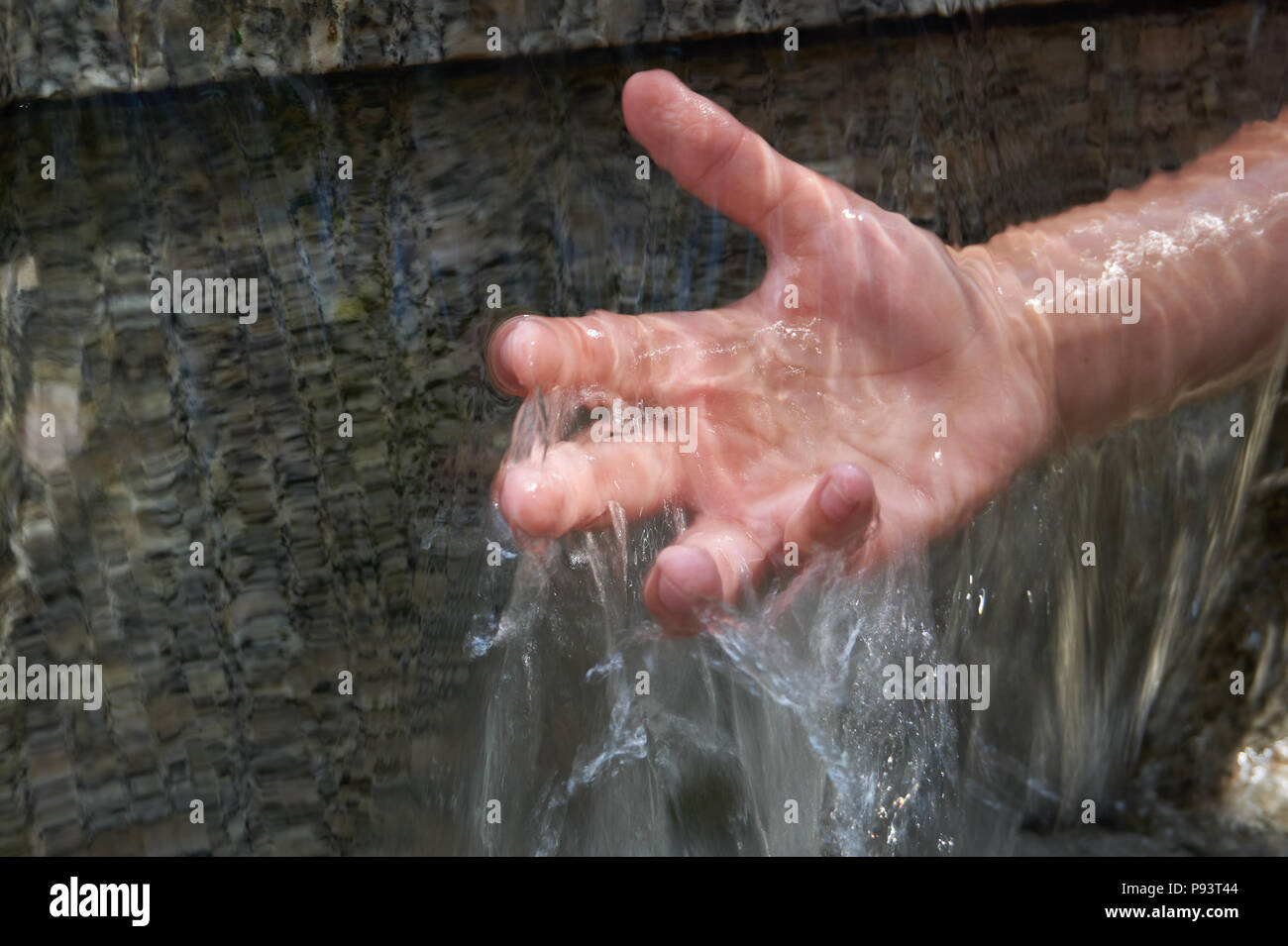 Teenager's hand under cascade of running water. Gray natural marble ...