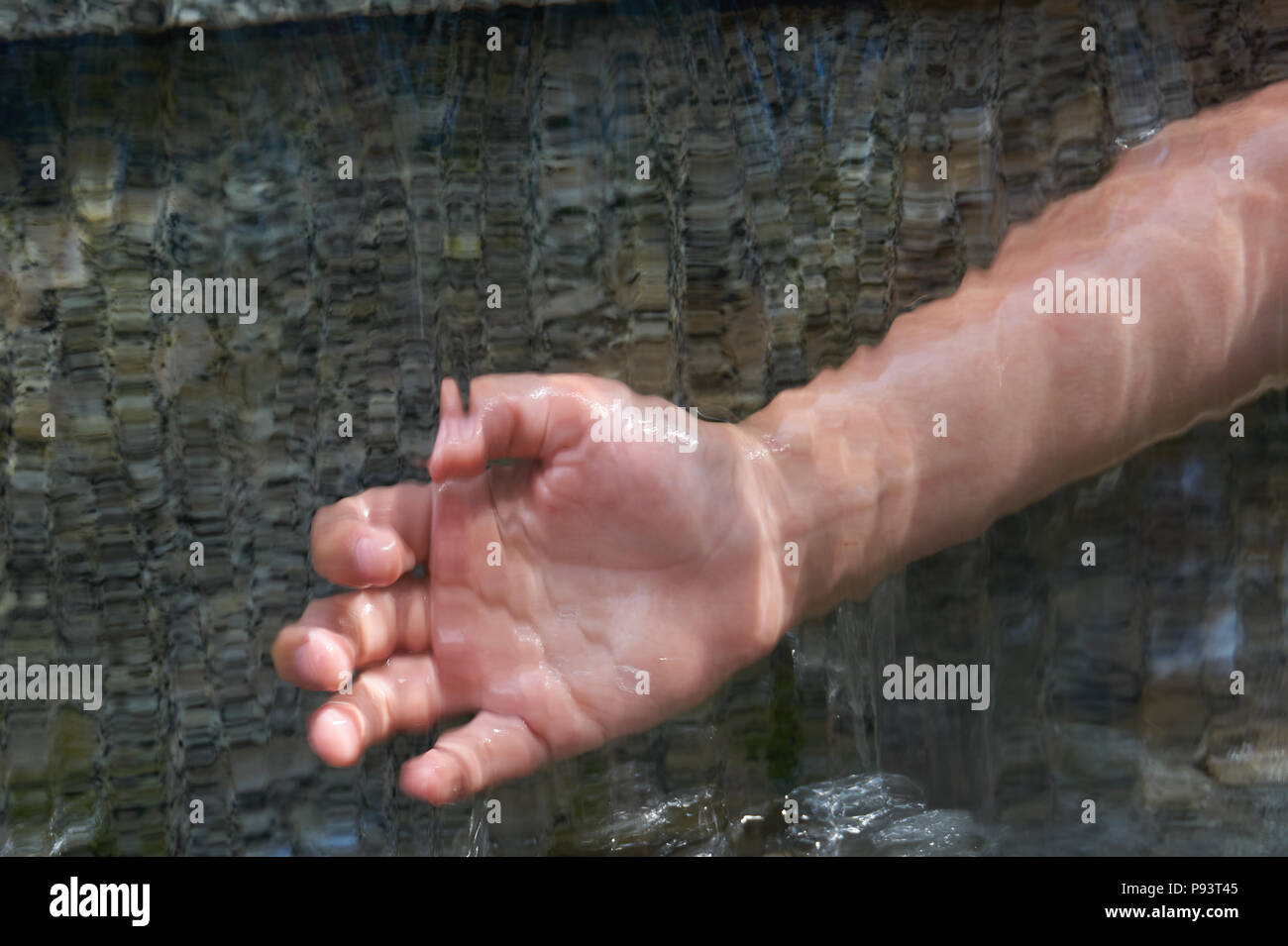 Teenager's hand under cascade of running water. Gray natural marble ...