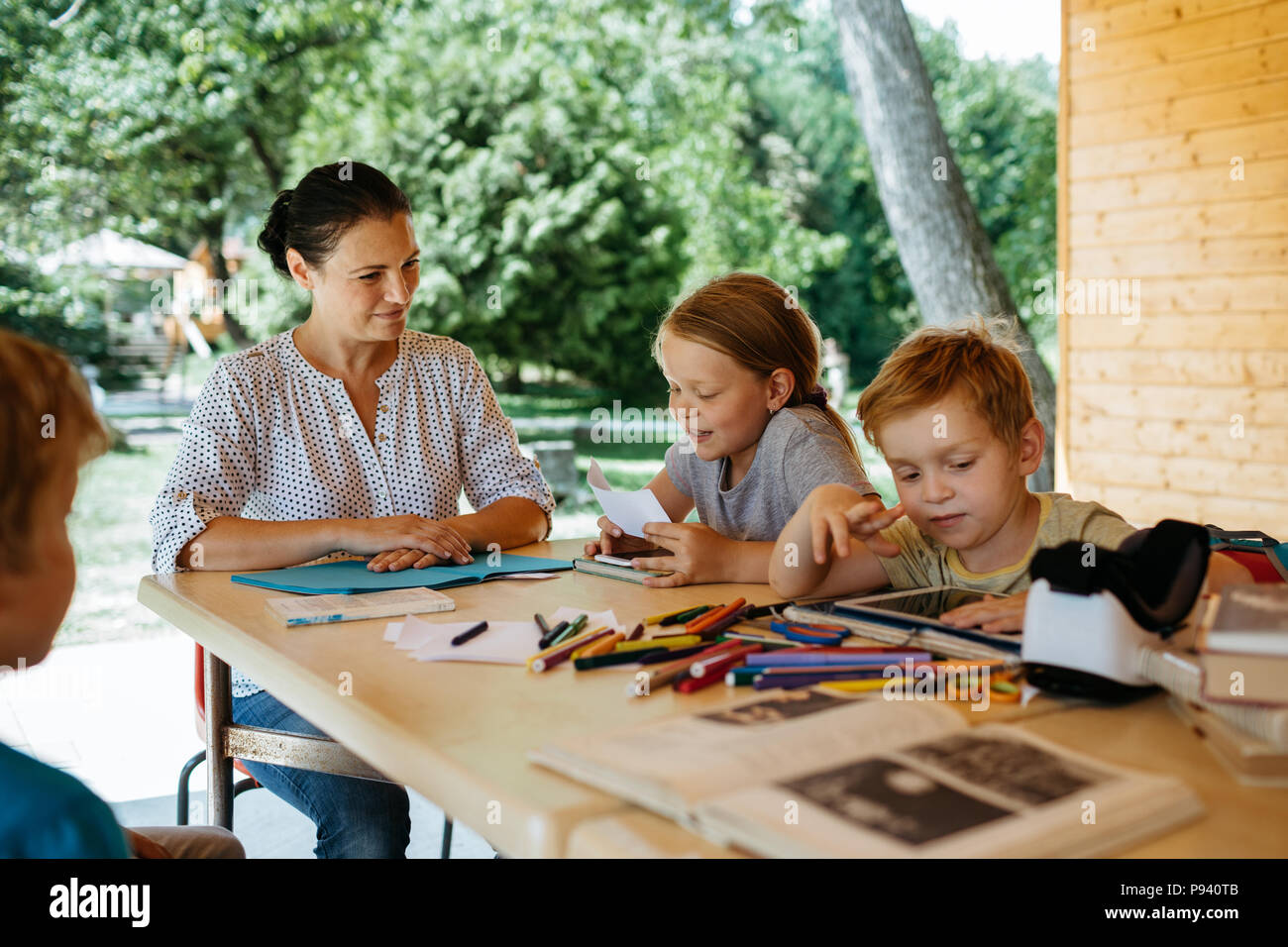 Young school girl reading aloud to her mother and class mates ...