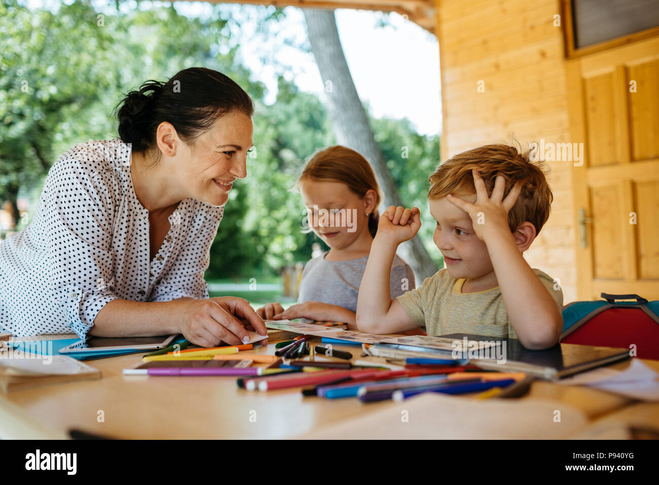 Teacher and students reading books together. Friendly teacher listening ...