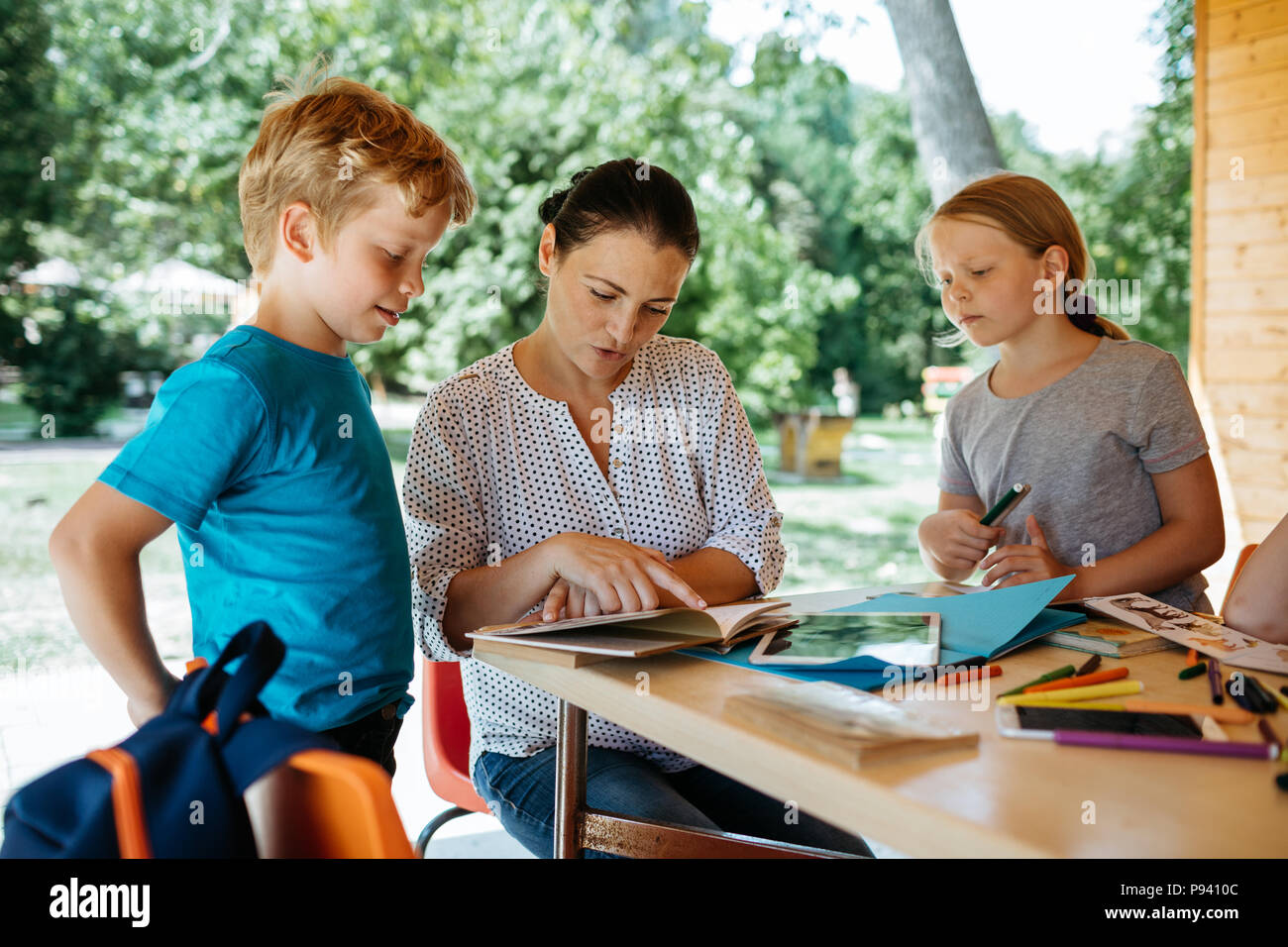 Schoolchildren learning with a teacher and listening to her. Teacher ...