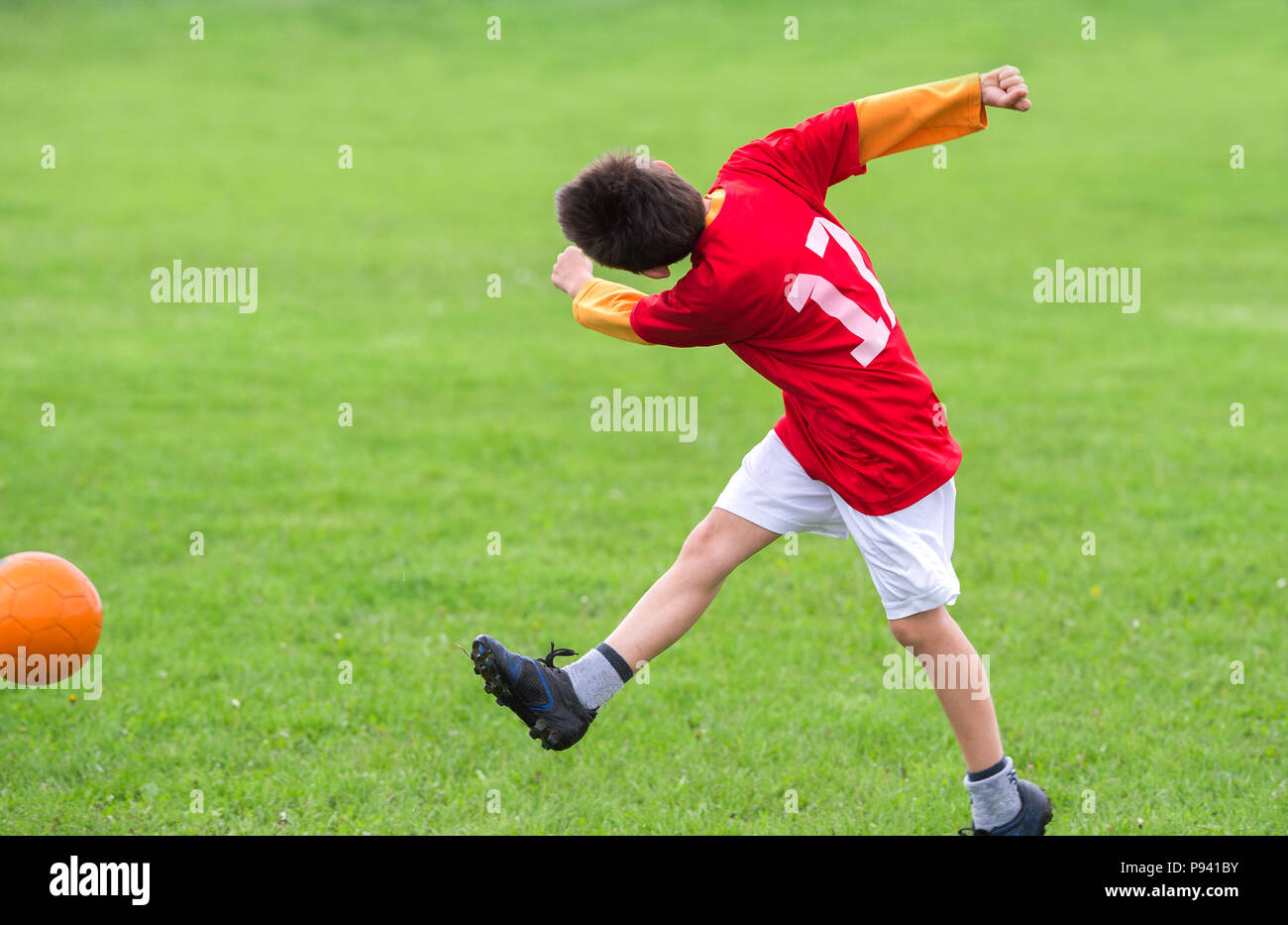 Kid kicking a soccer ball on the field Stock Photo - Alamy