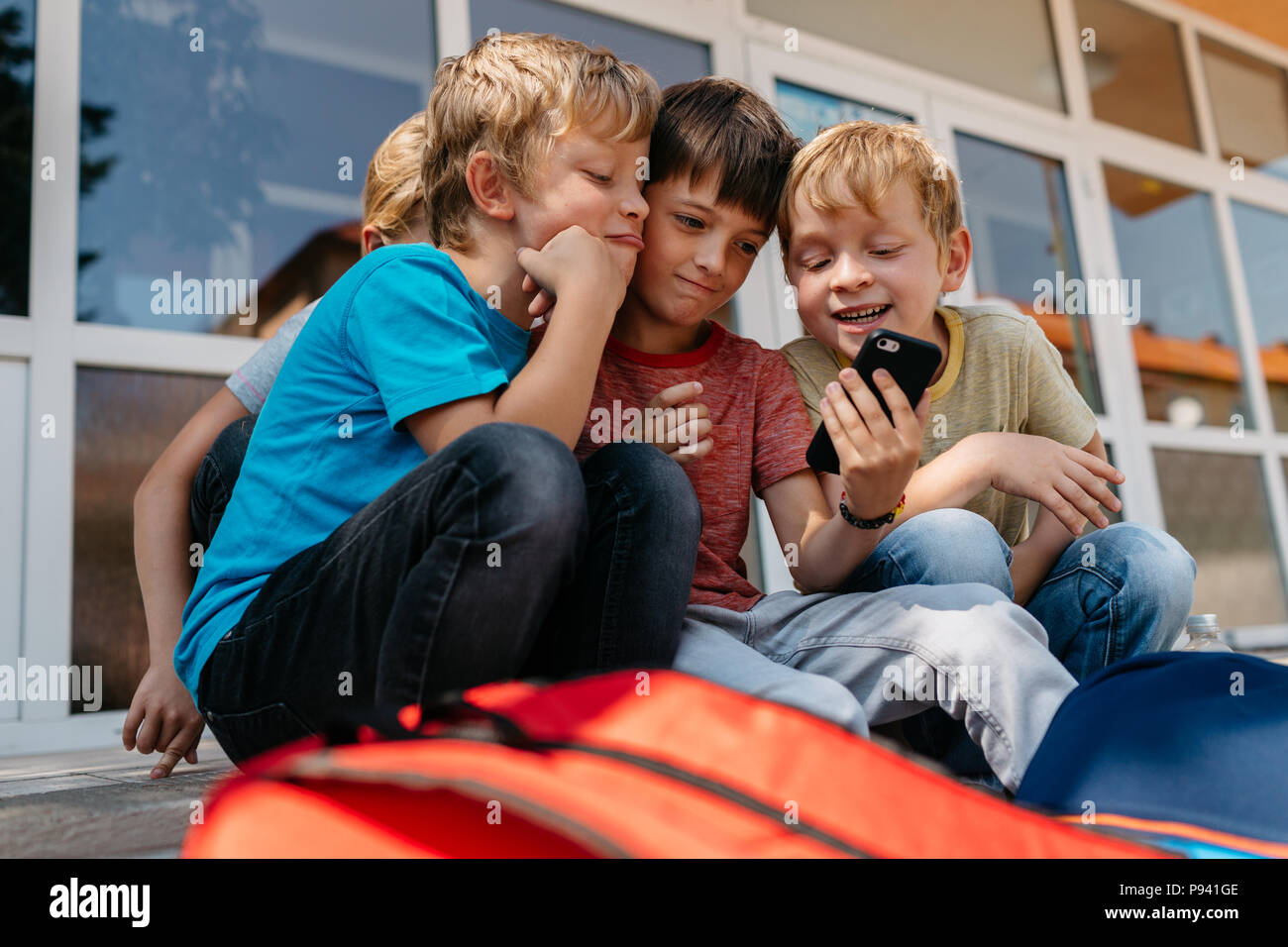 Children with a cell phone taking a selfie outside of school. Group of ...