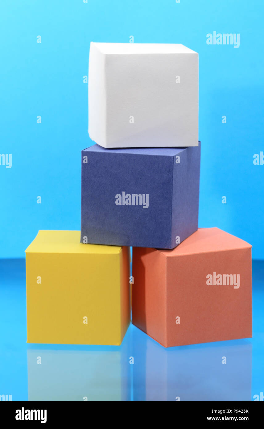 Four various colored paper cubes isolated on blue background Stock ...
