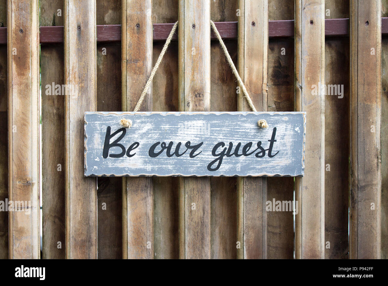 Photo of wooden table with lettering 'Be our guest' on the wooden ...