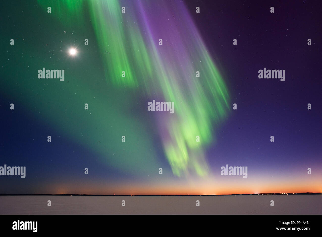 Vivid display of Northern Lights and Moon above frozen lake after ...