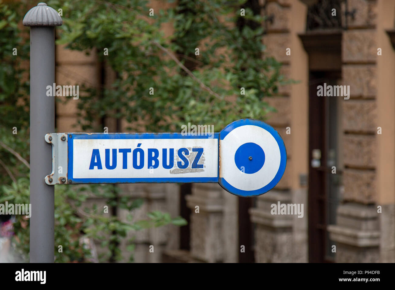 A blue and white bus stop sign that says autobusz in Hungarian in ...