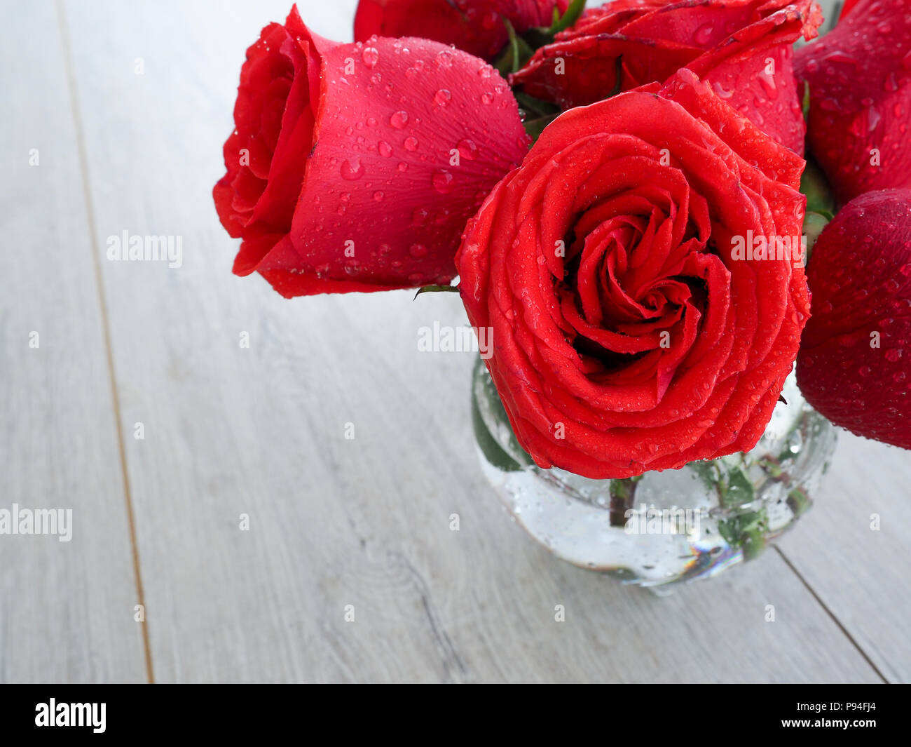 a bouquet of bright red roses in a glass vase Stock Photo - Alamy