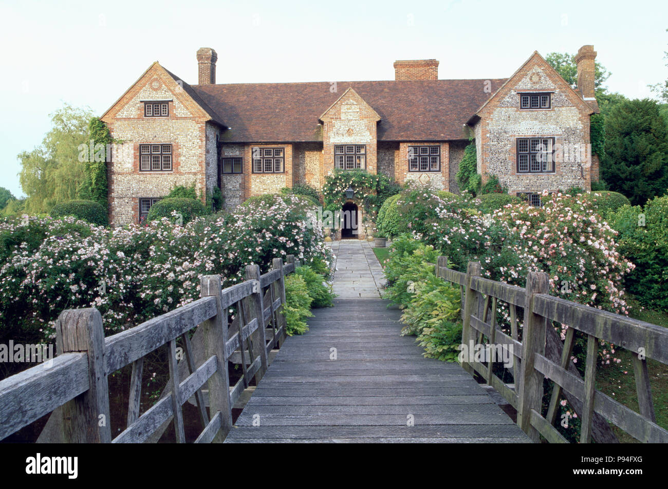 Wooden bridge and pink roses in front of large country house in summer ...