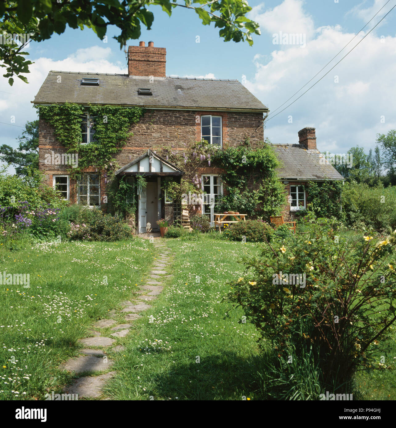 Path across lawn to traditional brick Victorian country cottage Stock ...