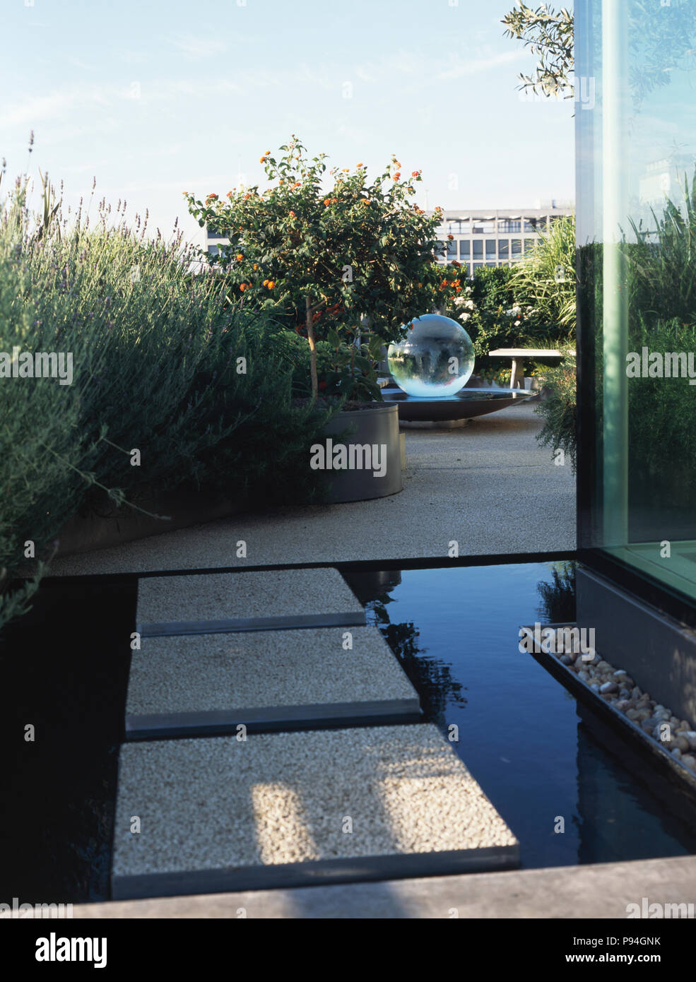 Paving across shallow pool on city roof terrace with bubble fountain ...