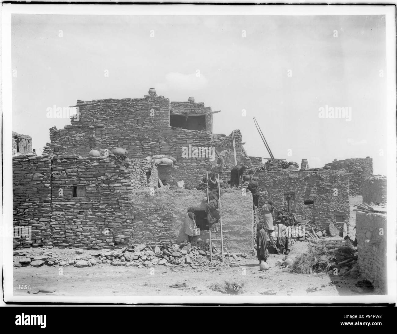 A group of Hopi Indian women building an adobe house in the village of ...