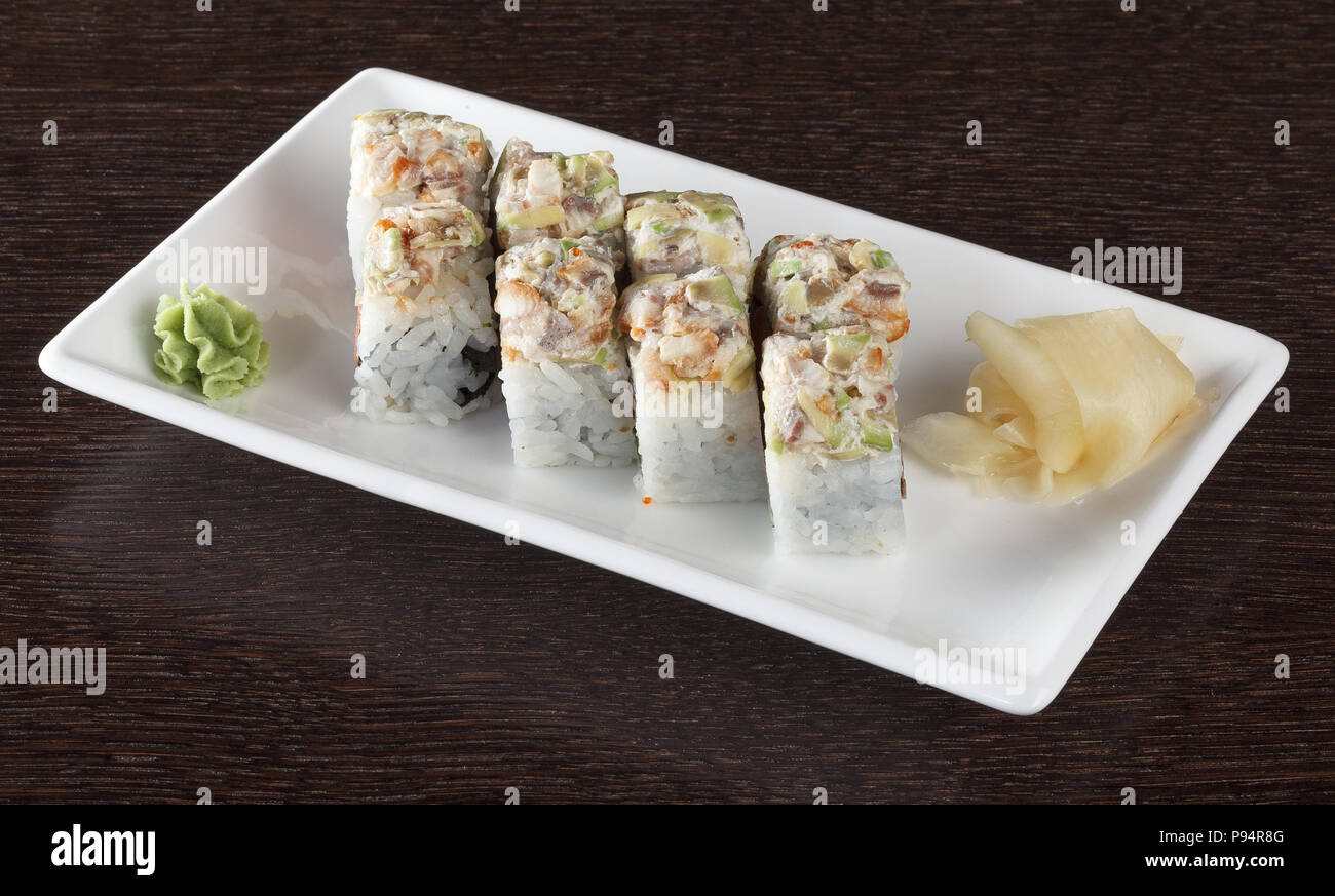 Sushi rolls with salmon and tuna on a plate on wooden table. Side view ...