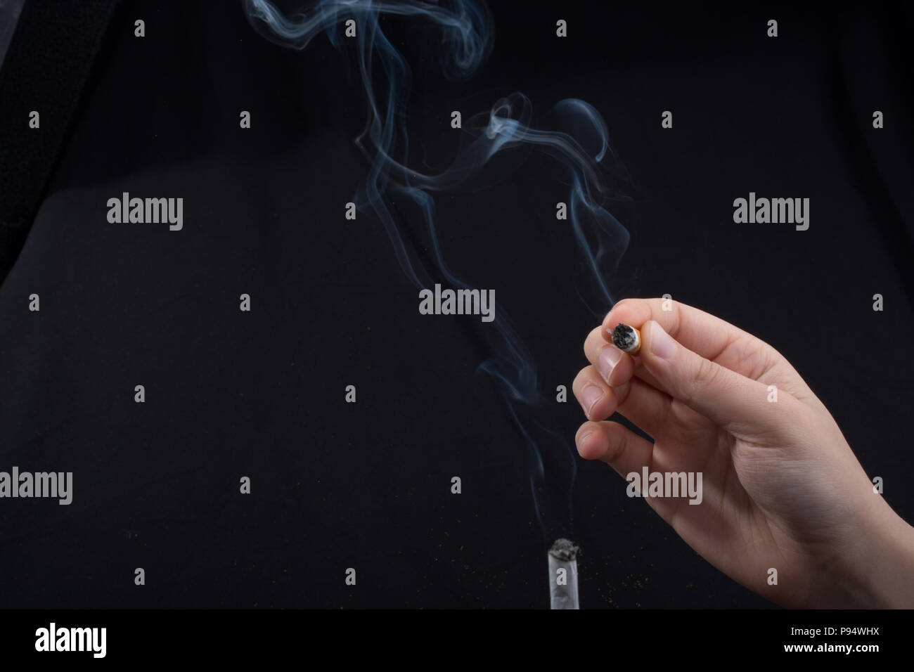 Hand is holding smoking cigarette with smoke around Stock Photo - Alamy